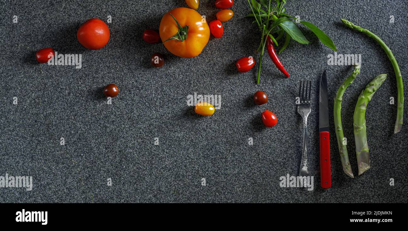 Food border with green asparagus, red and orange tomatoes and red ...
