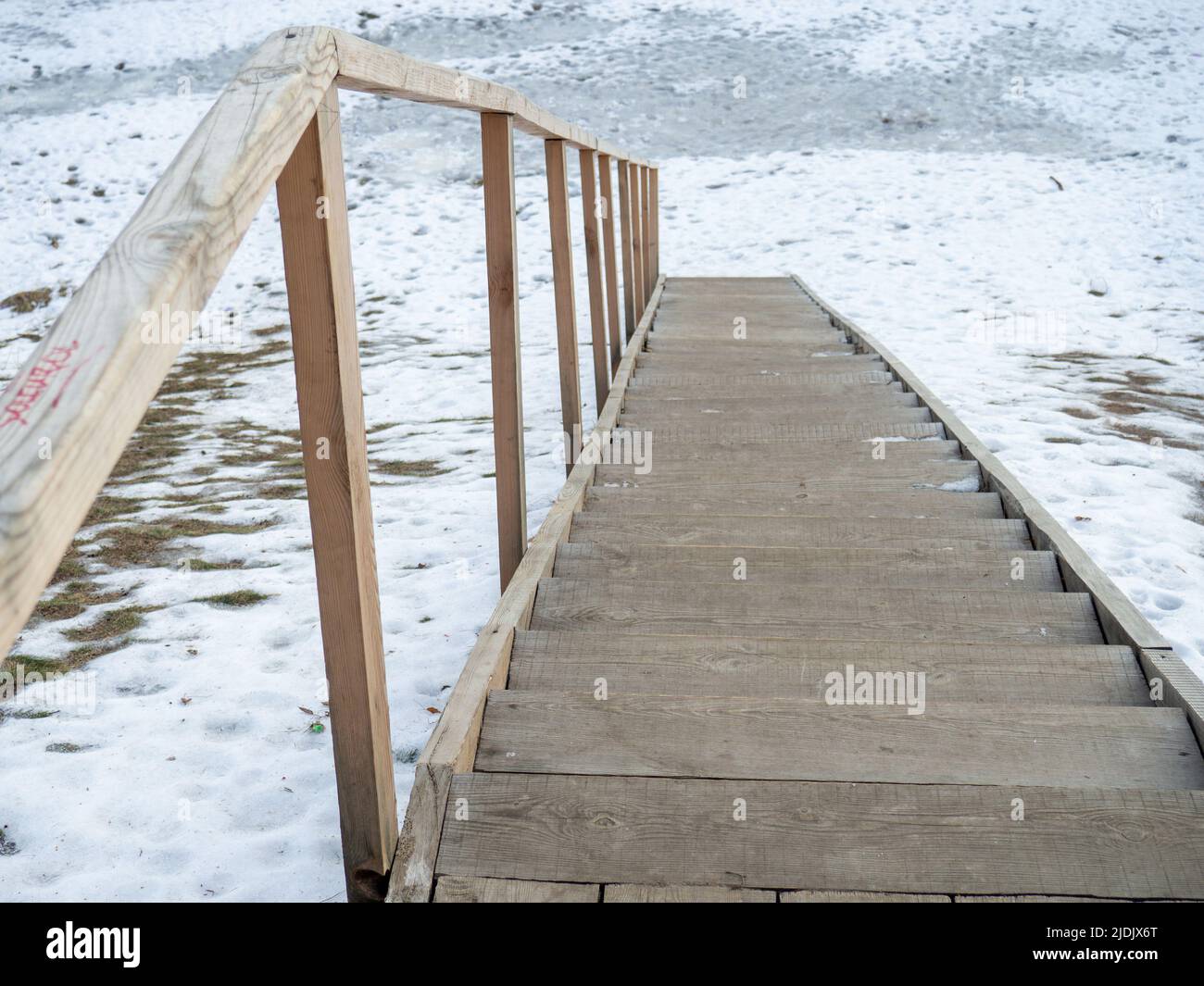 Wooden ladder in the snow. Descent to the water Stock Photo - Alamy
