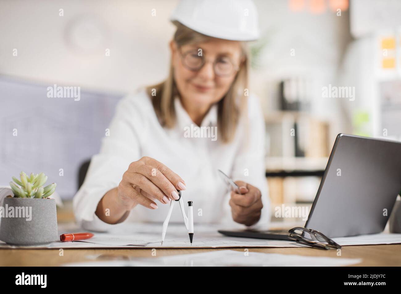 Focus on hand with compass. Senior engineer woman in white helmet and ...