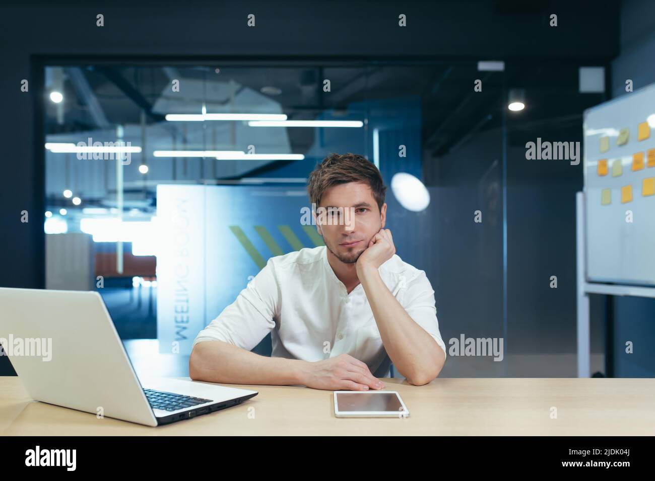 Boring working day. Portrait of a young man sitting in the office at ...