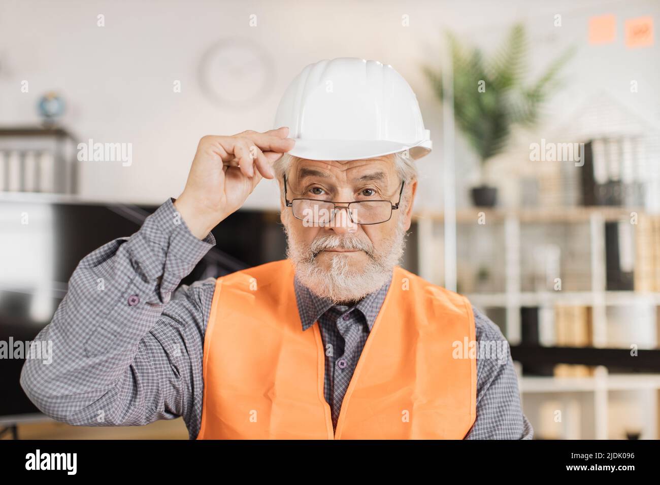 Portrait of mature architect wearing white construction helmet indoors ...