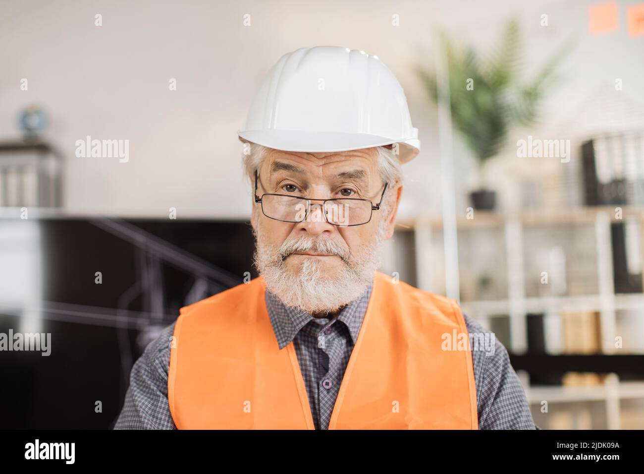 Portrait of mature architect wearing white construction helmet indoors ...