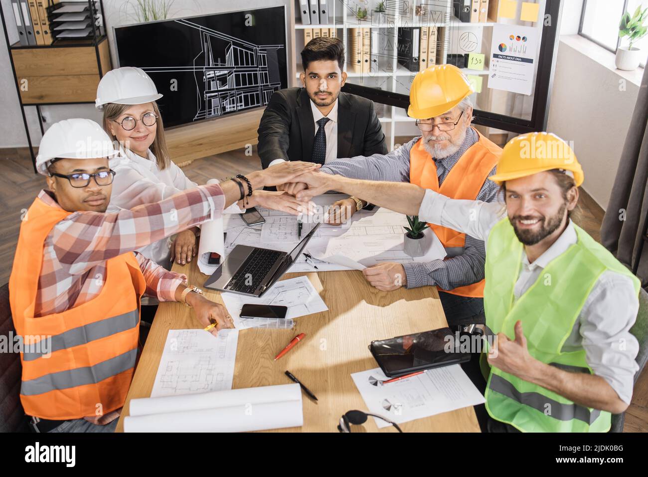 Happy multiracial architects, engineers and designers stacking their ...