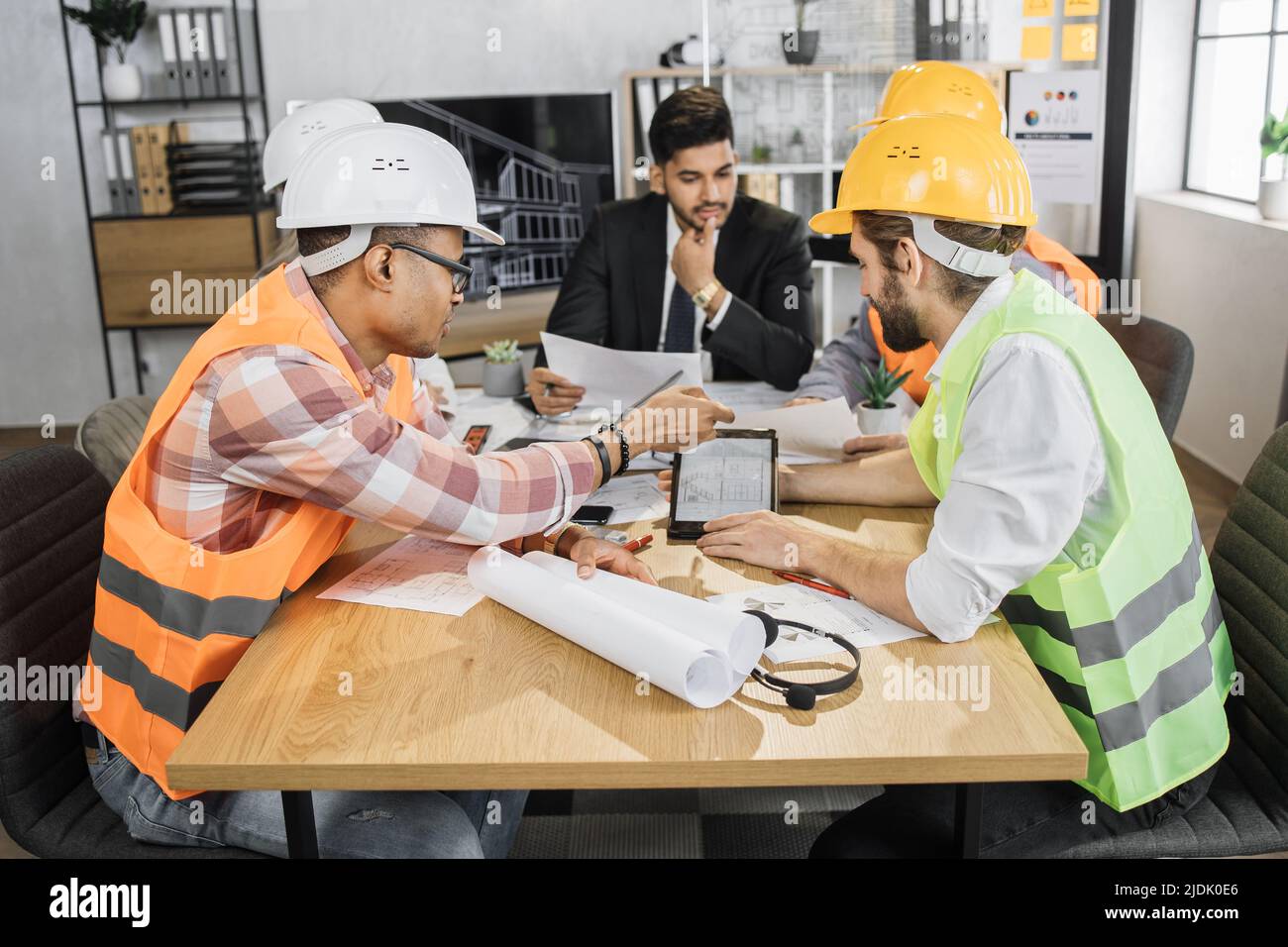 Multicultural workers in reflective vest and helmets using tablet for ...