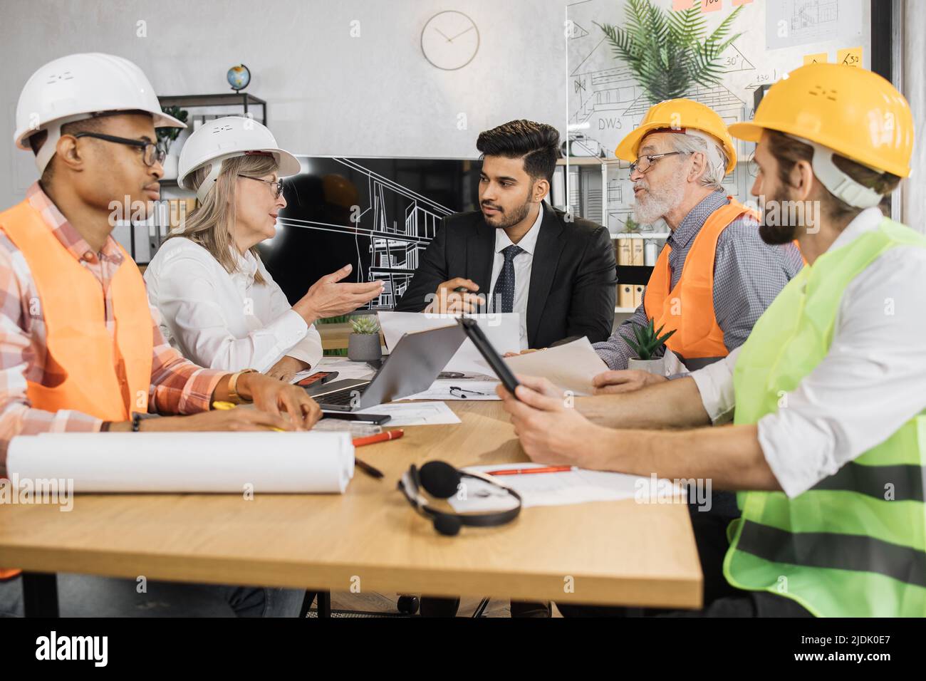 Group of five multiracial people architects sitting at the desk in ...