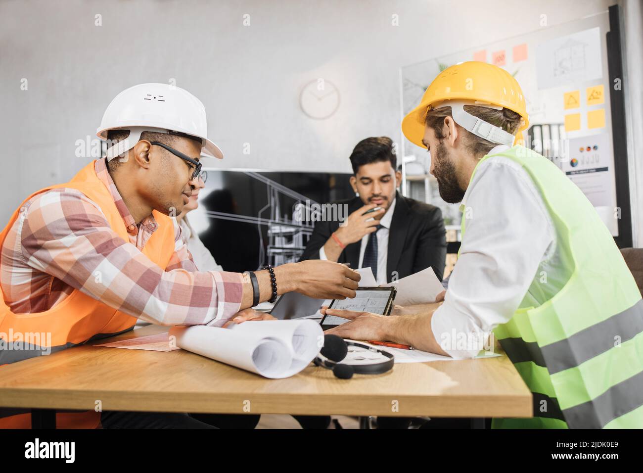Multicultural workers in reflective vest and helmets using tablet for ...