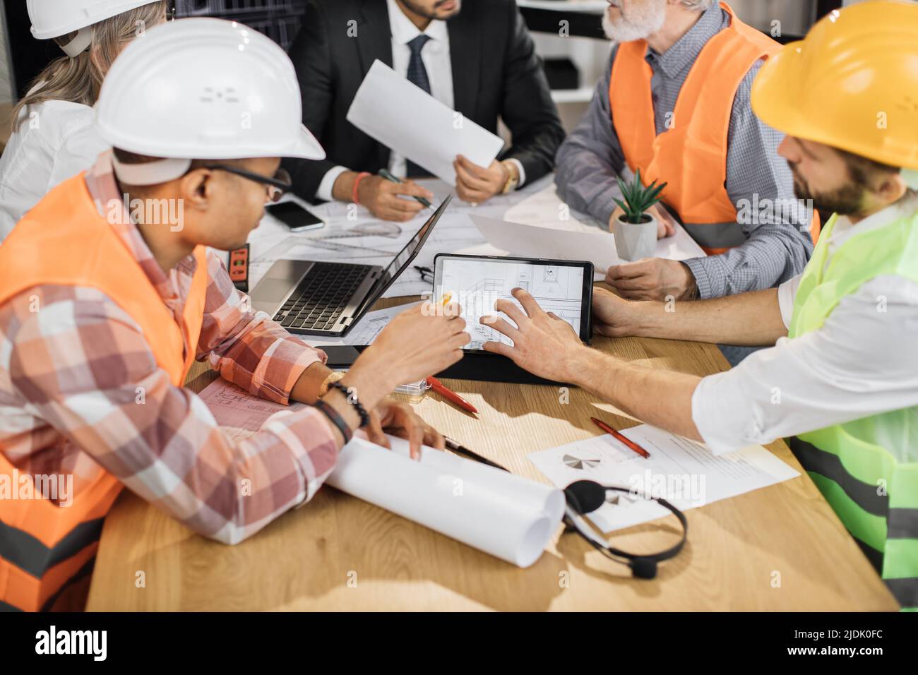 Construction team analysing blueprints during business meeting at ...