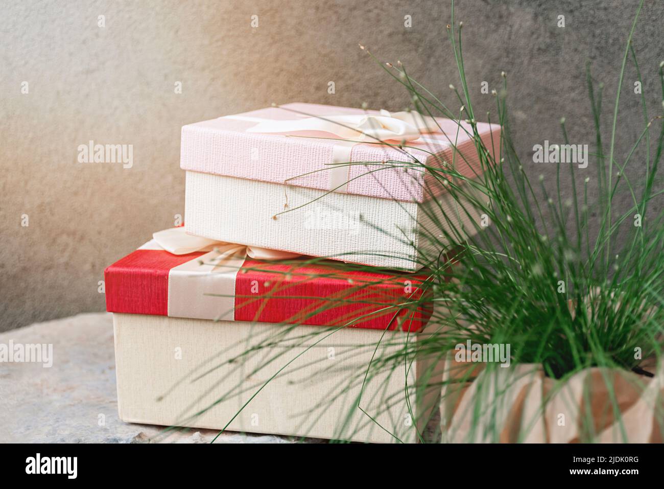 Front view of two beautiful gift boxes with satin ribbon on a concrete ...