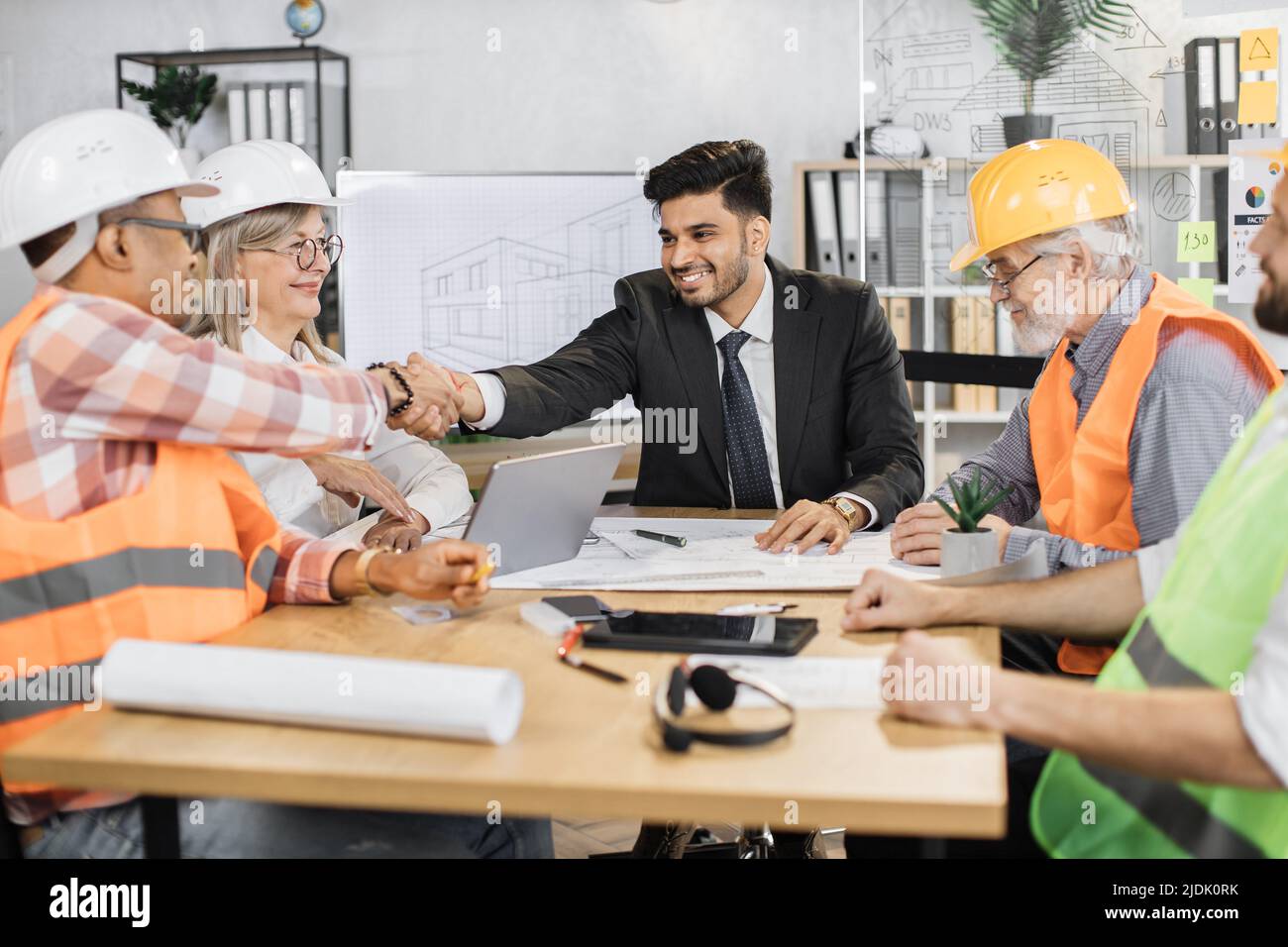 Multiethnic architects, designers and engineers sitting at table and ...