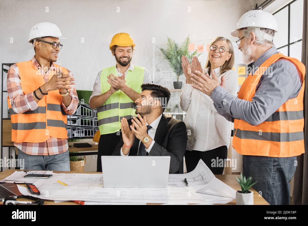 Team of multinational engineers rejoices clapping their hands looking ...