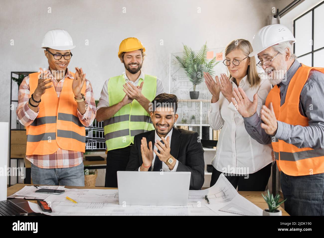 Team of multinational engineers rejoices clapping their hands looking ...
