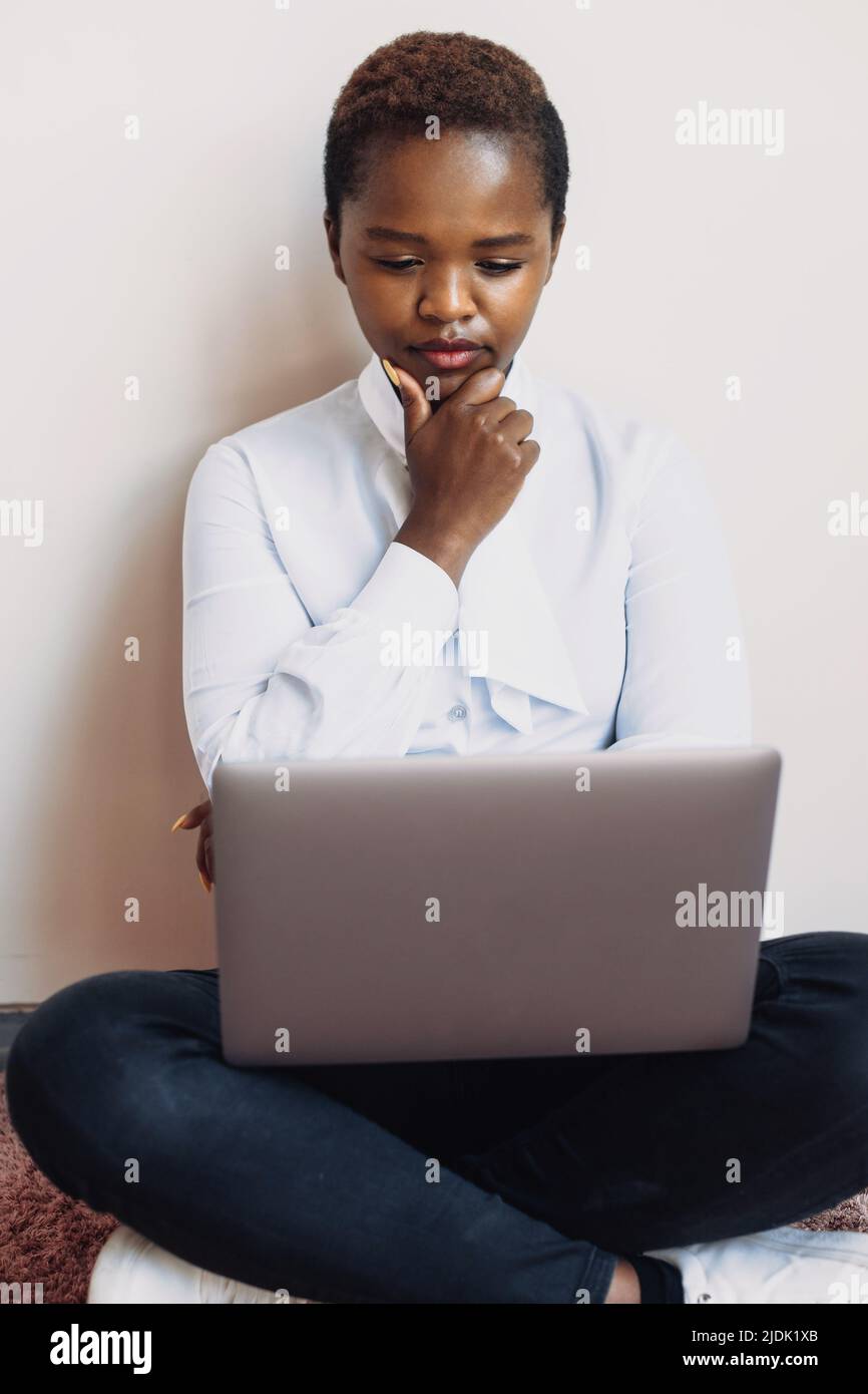Pensive afro freelancer woman, looking at laptop screen while working ...