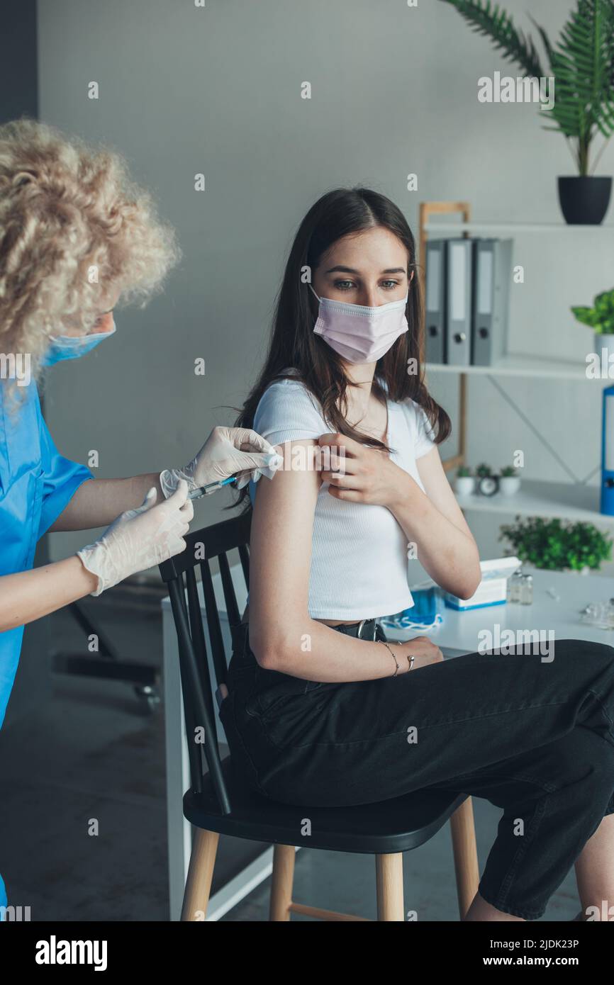 Nurse in medical face mask disinfecting caucasian woman patient ...
