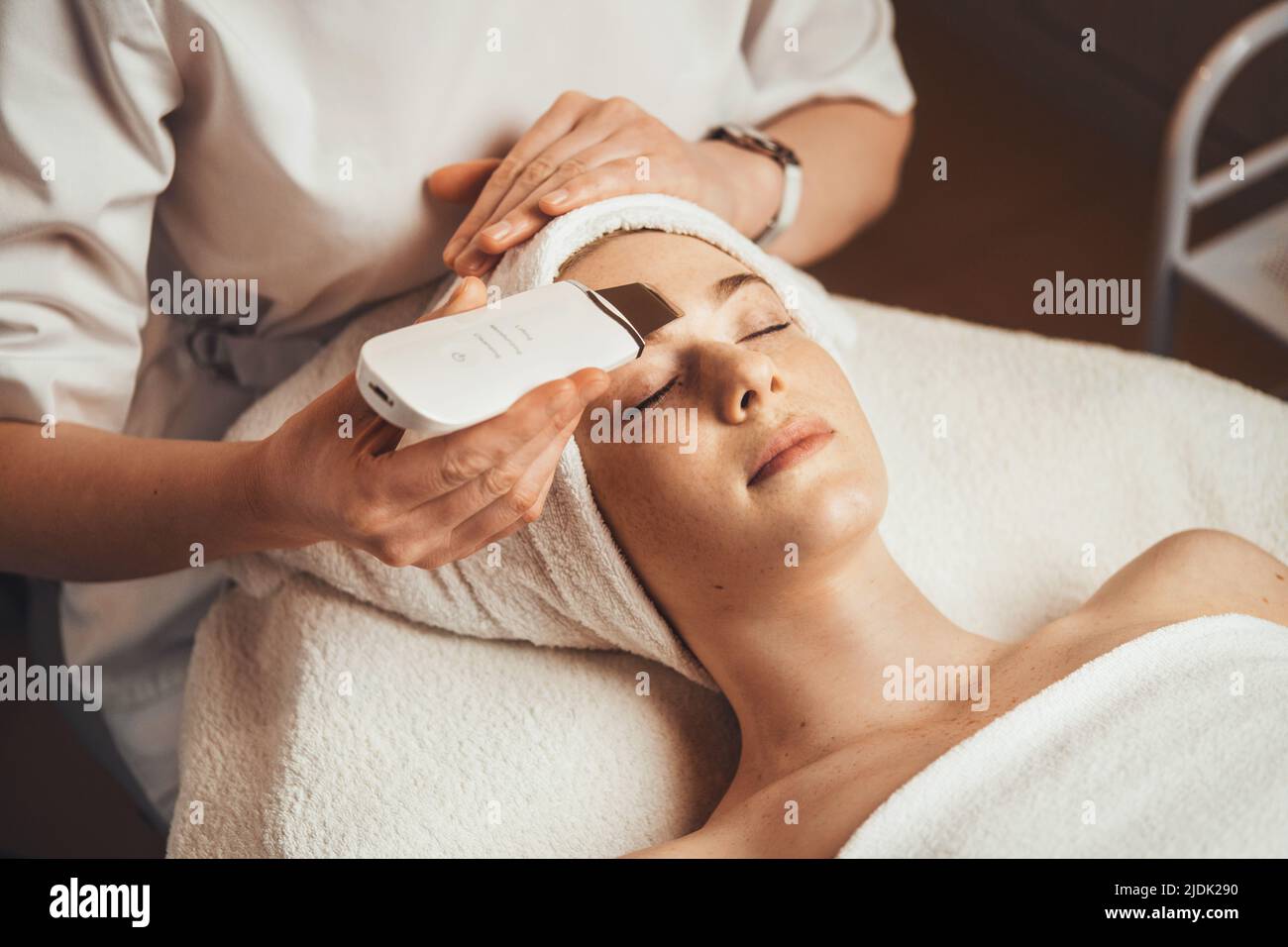 Caucasian woman receiving facial procedure of cleansing the skin with ...