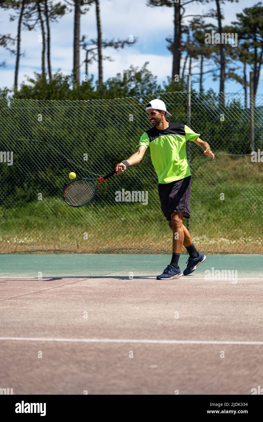 Tennis player hitting forehand at ball with racket on court Stock Photo ...