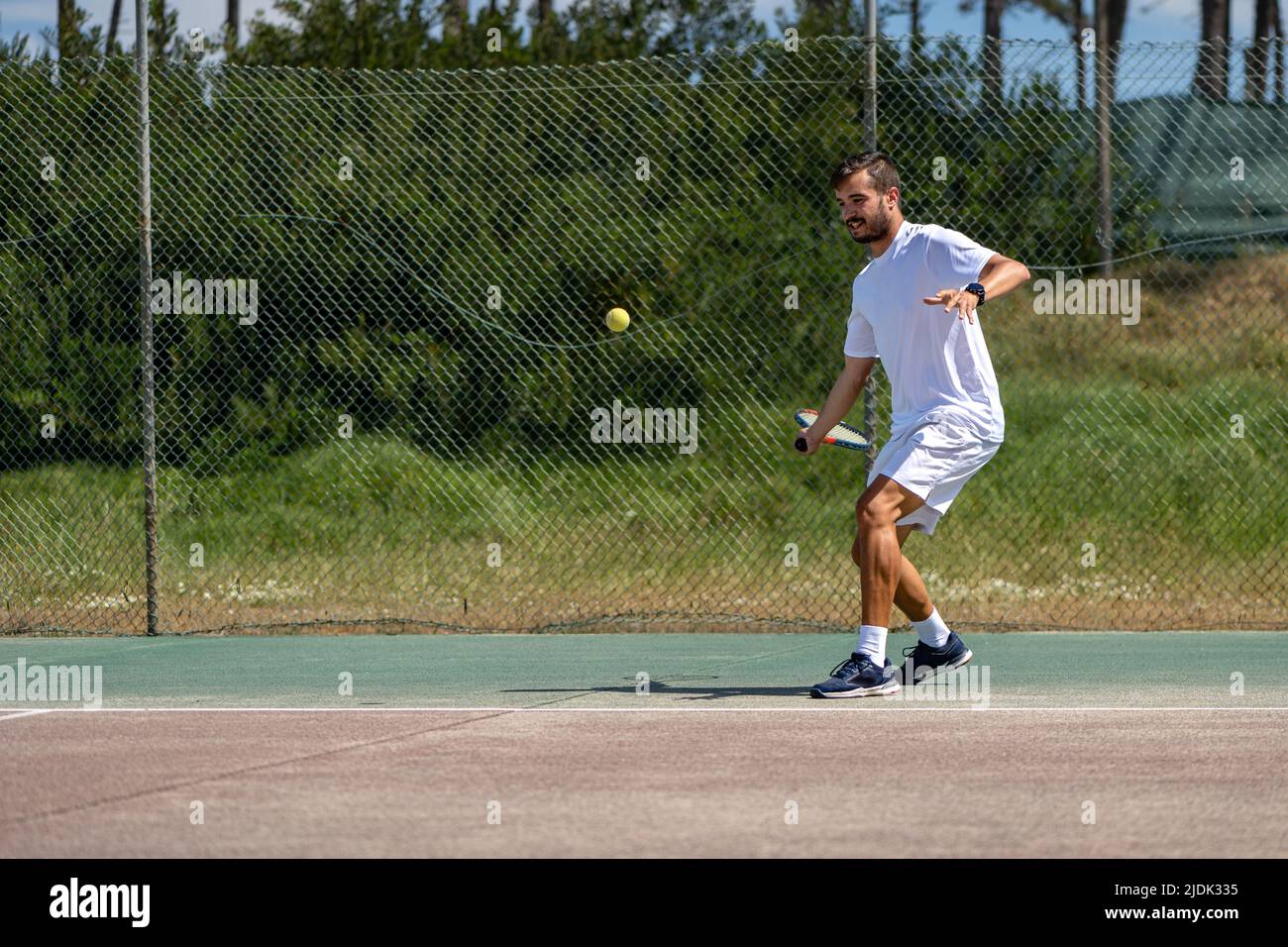 Tennis player hitting forehand at ball with racket on court Stock Photo ...