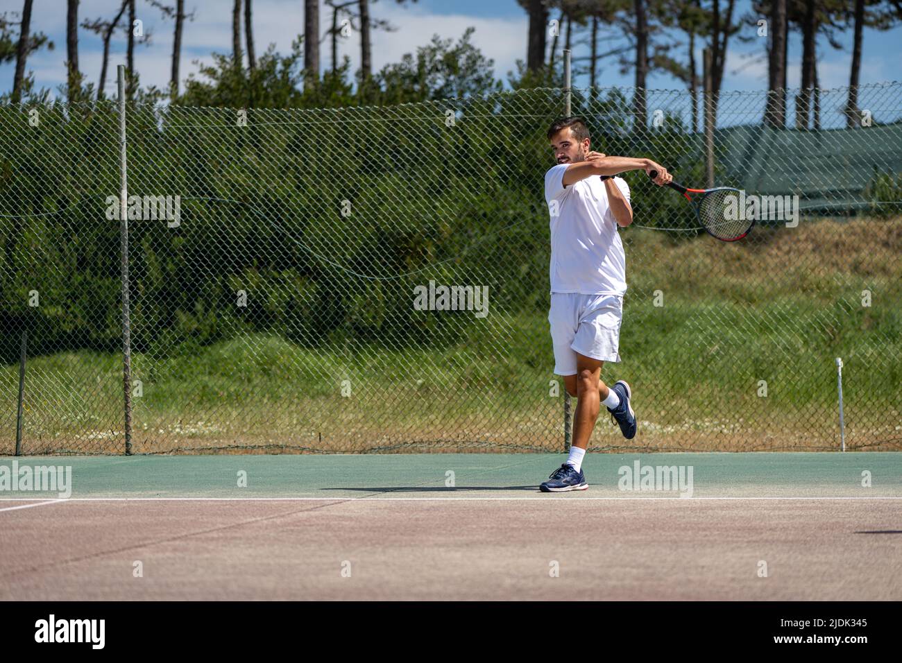 Tennis player hitting forehand at ball with racket on court Stock Photo ...