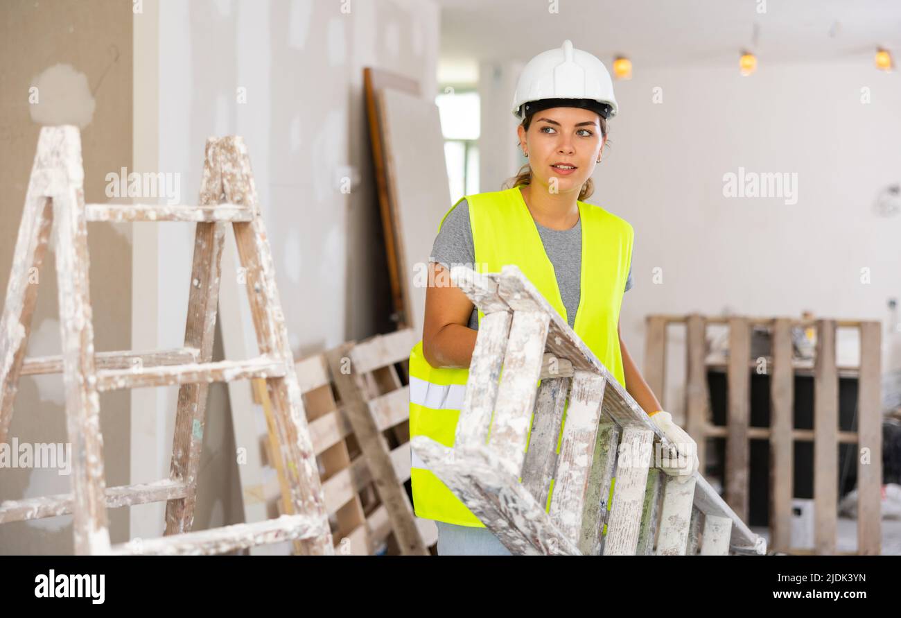 Female construction worker carrying ladder during renovation works ...