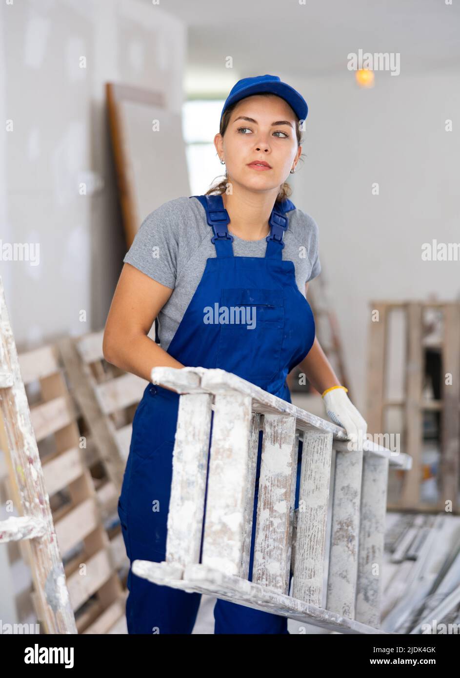 Female construction worker carrying ladder during renovation works ...