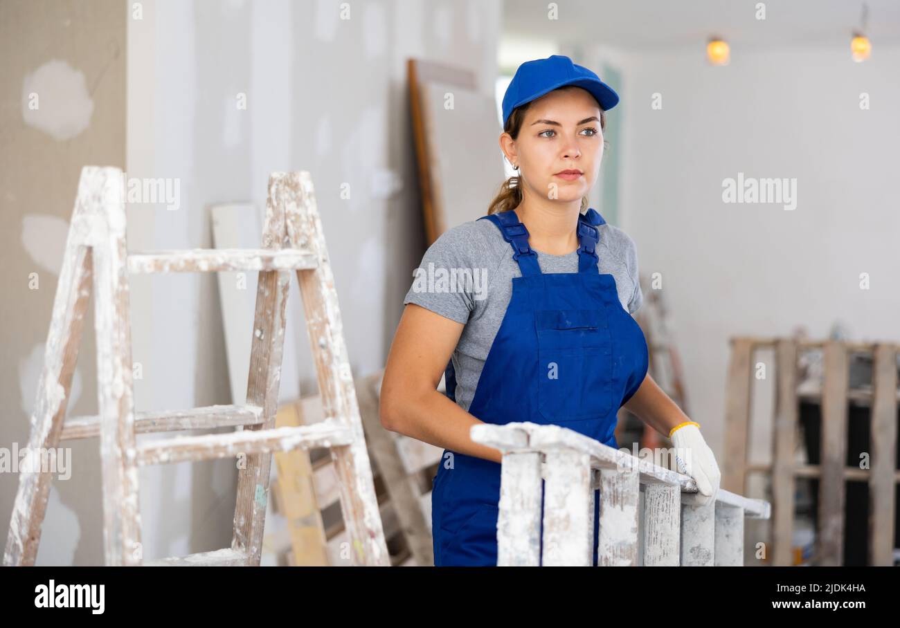 Female construction worker carrying ladder during renovation works ...