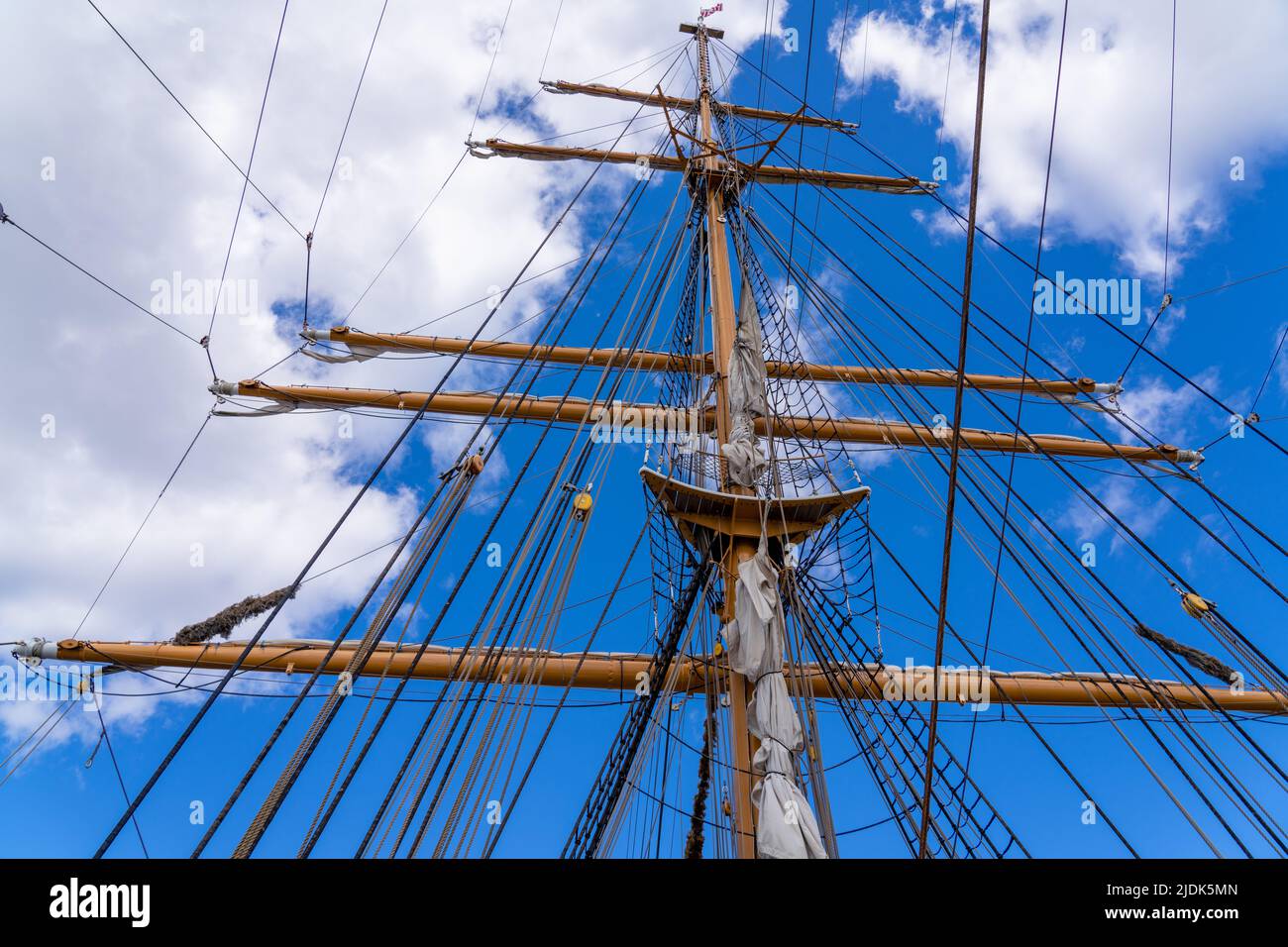 Large mast of a sailing ship with the blue sky and clouds in the ...