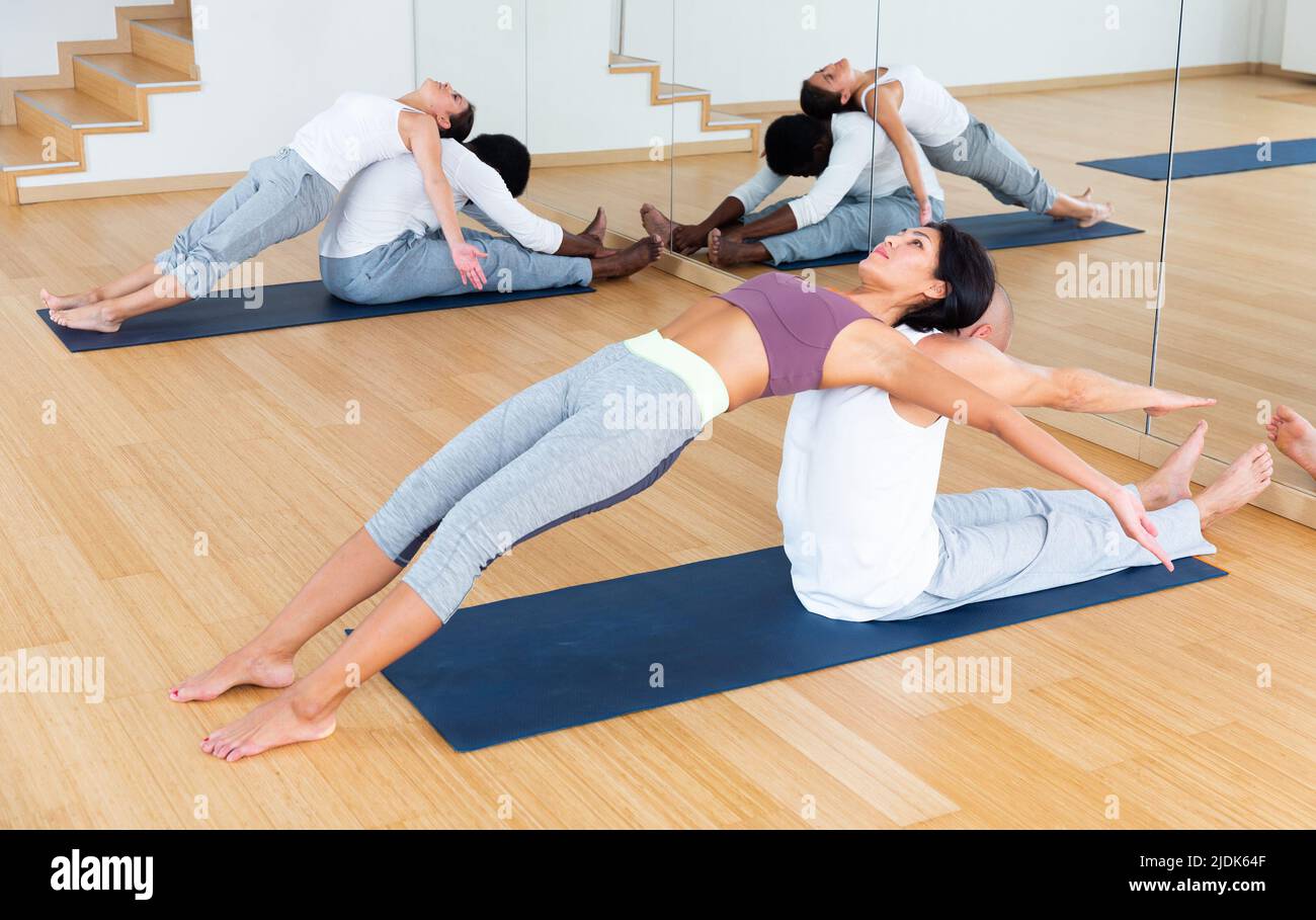 People doing stretching exercises in pairs in fitness center Stock ...