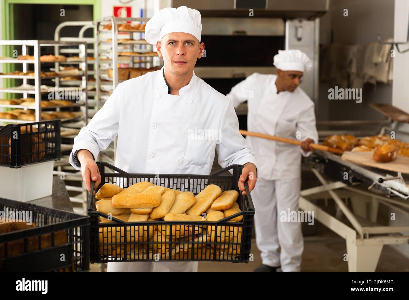 Positive bakery worker lays fresh bread Stock Photo - Alamy