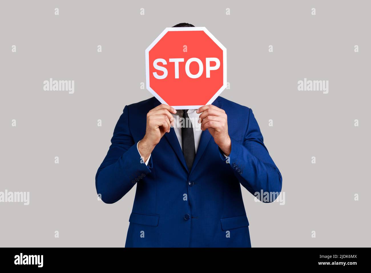Portrait of man hiding face behind Stop symbol, red traffic sign ...