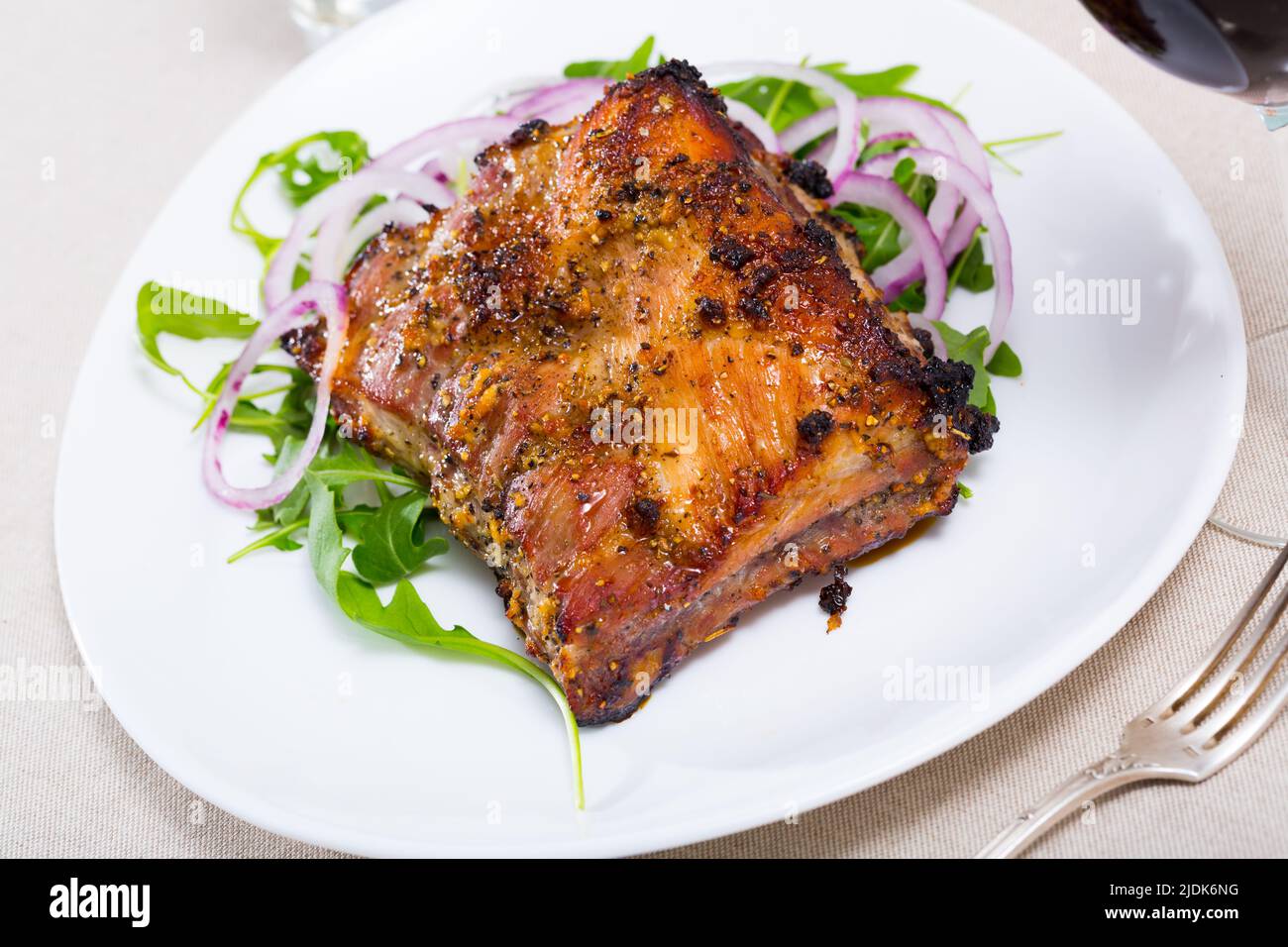 Tasty pork ribs baked under sauce, served with arugula and onion salad ...