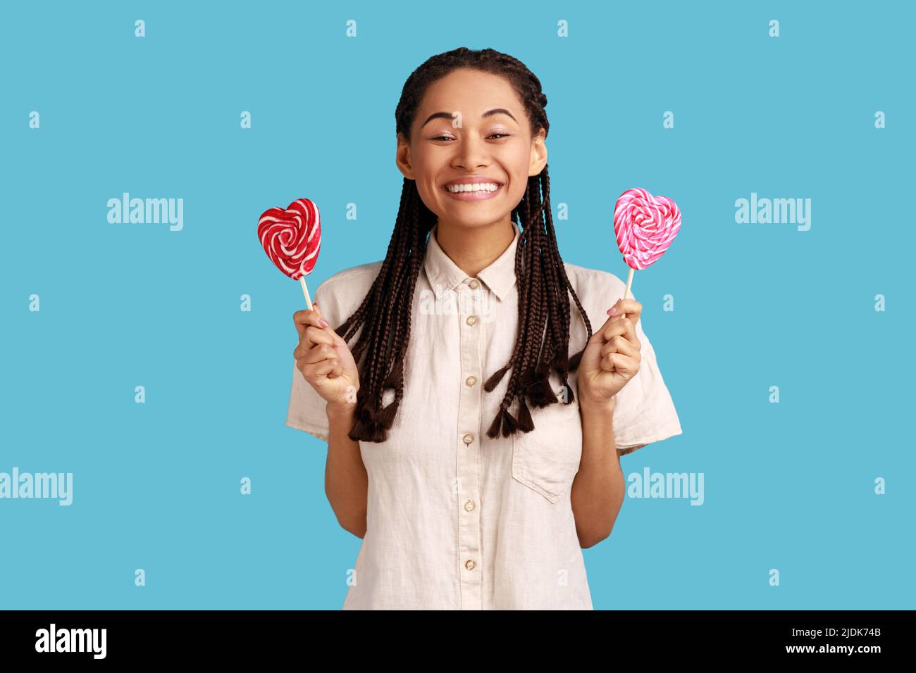 Portrait of cheerful playful woman with dreadlocks holding sweet heart ...
