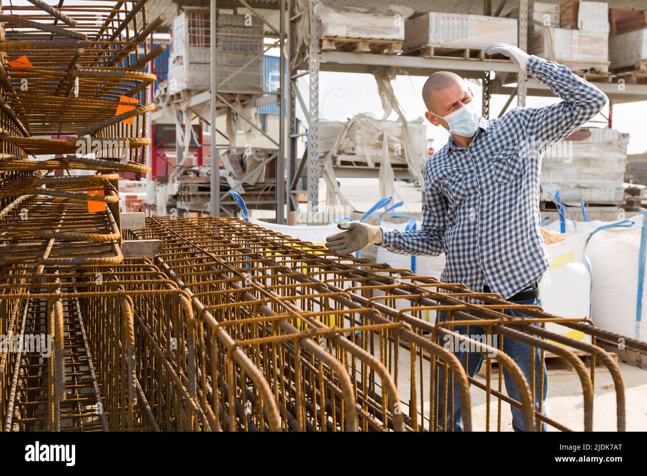 Worker in protective mask prepares metal rebar for loading onto truck ...