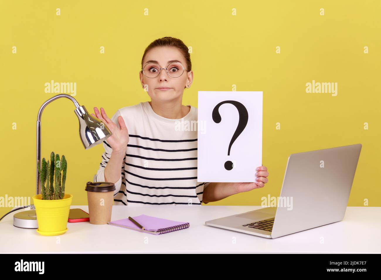 Smart woman office employee sitting on workplace and holding question ...
