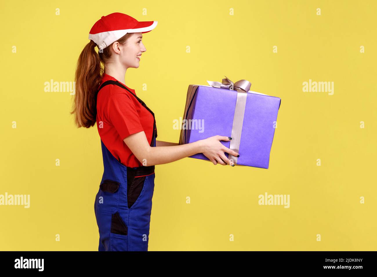 Side view portrait of positive delivery woman standing holding present ...