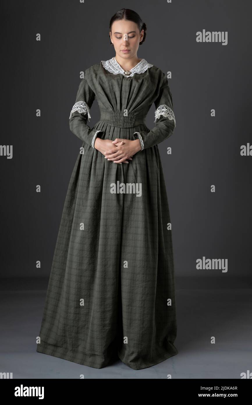 A Victorian maid servant or working class woman wearing a dark green ...