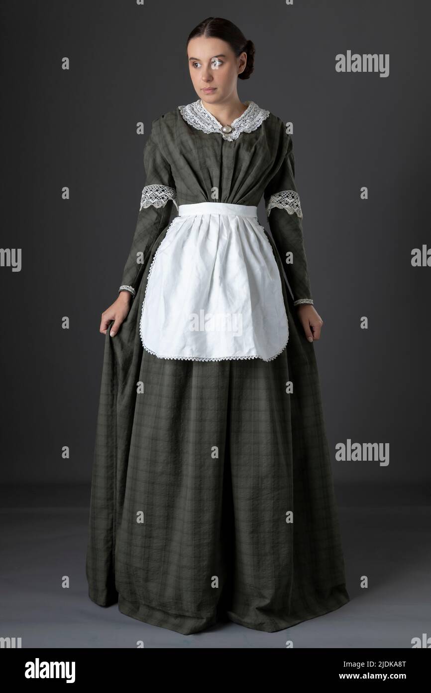 A Victorian maid servant or working class woman wearing a dark green ...