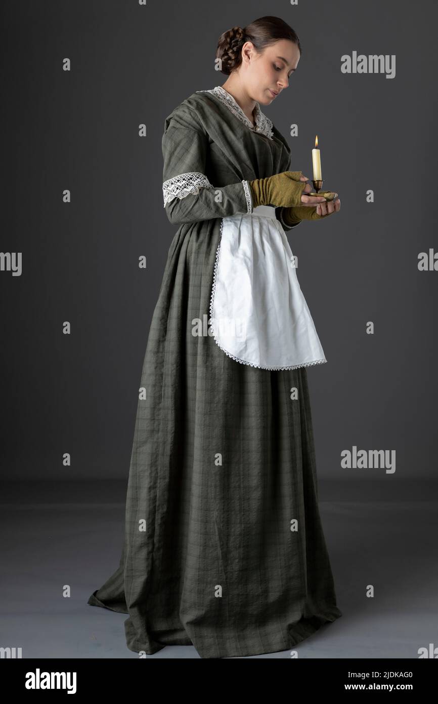 A Victorian maid servant or working class woman wearing a dark green ...