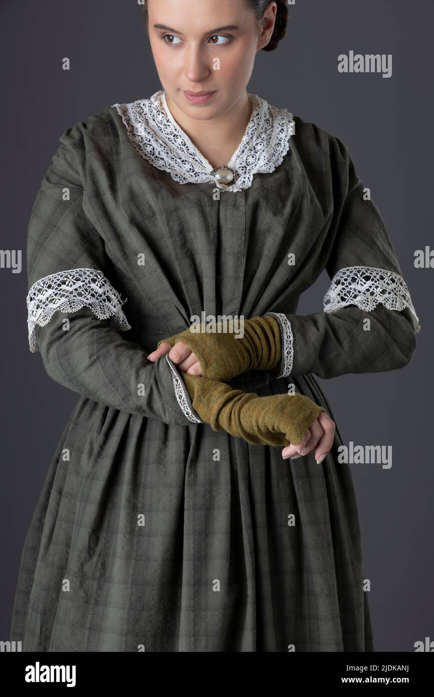 A Victorian maid servant or working class woman wearing a dark green ...