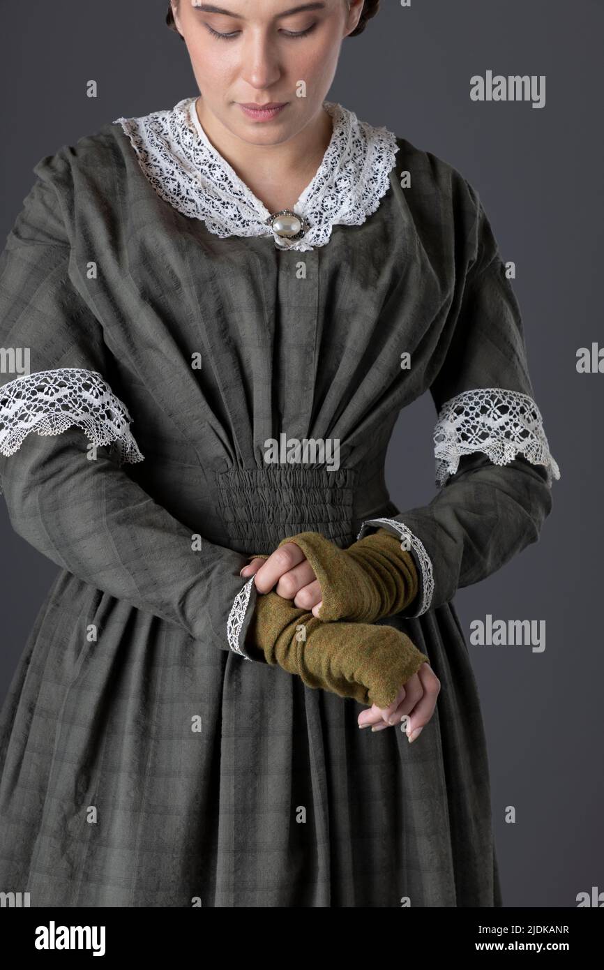 A Victorian maid servant or working class woman wearing a dark green ...