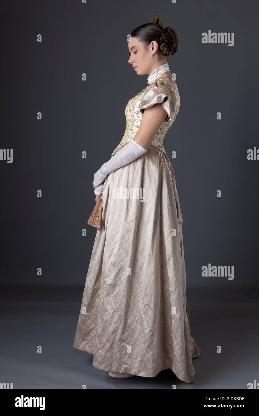 A Victorian woman wearing a gold evening dress, a pearl choker, and ...