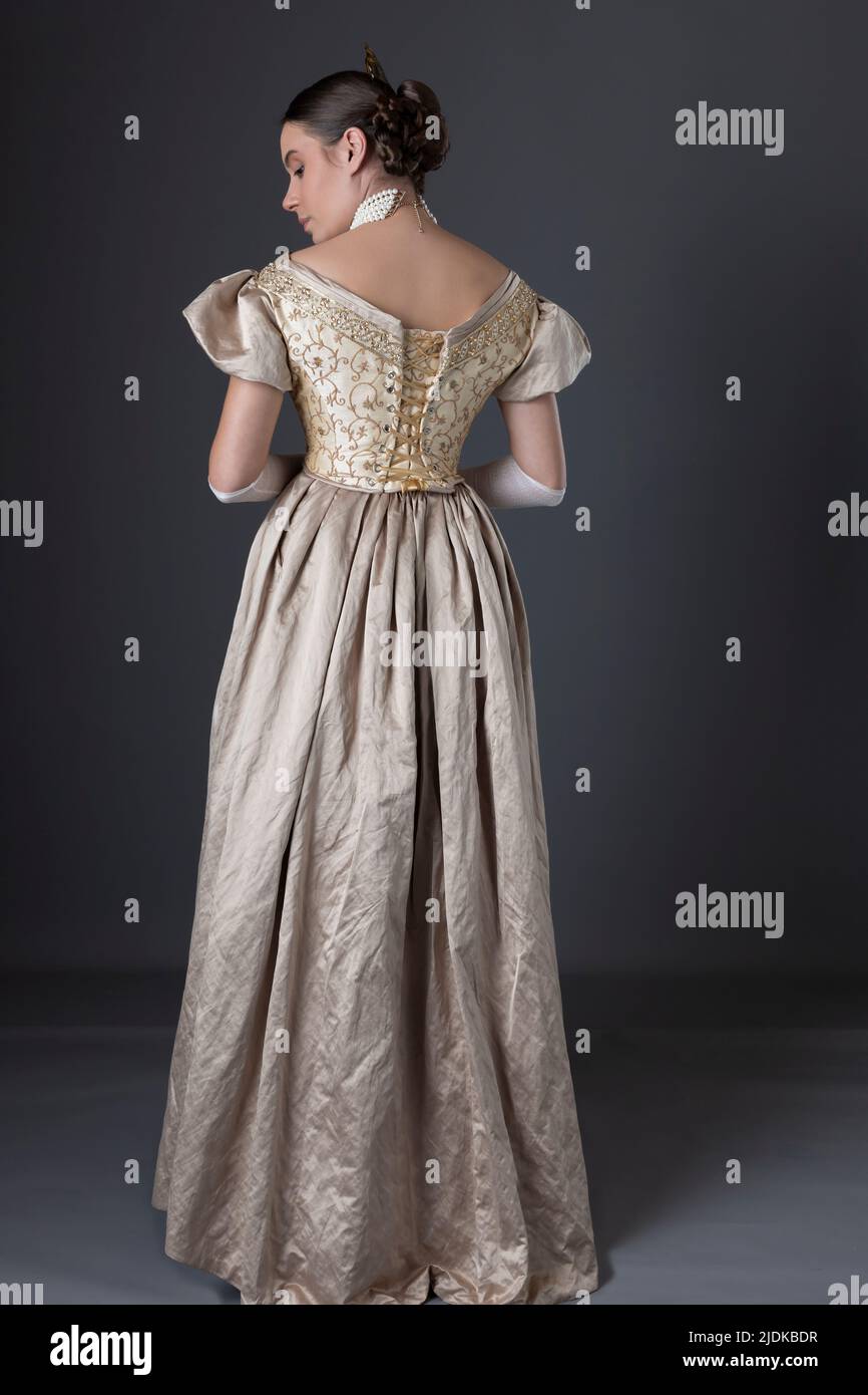 A Victorian woman wearing a gold evening dress, a pearl choker, and ...