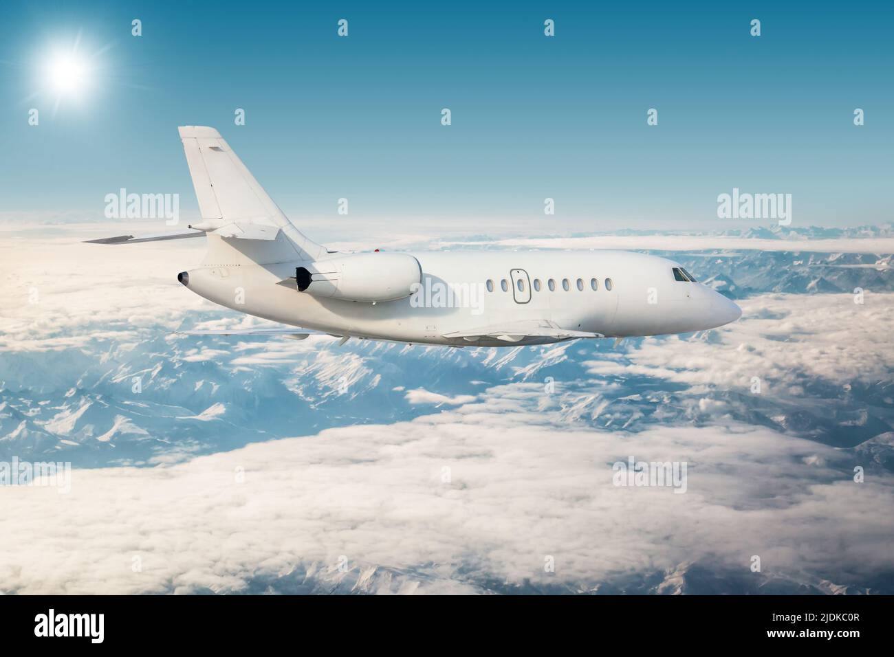 White modern luxury corporate aircraft flies over snow-covered mountain ...