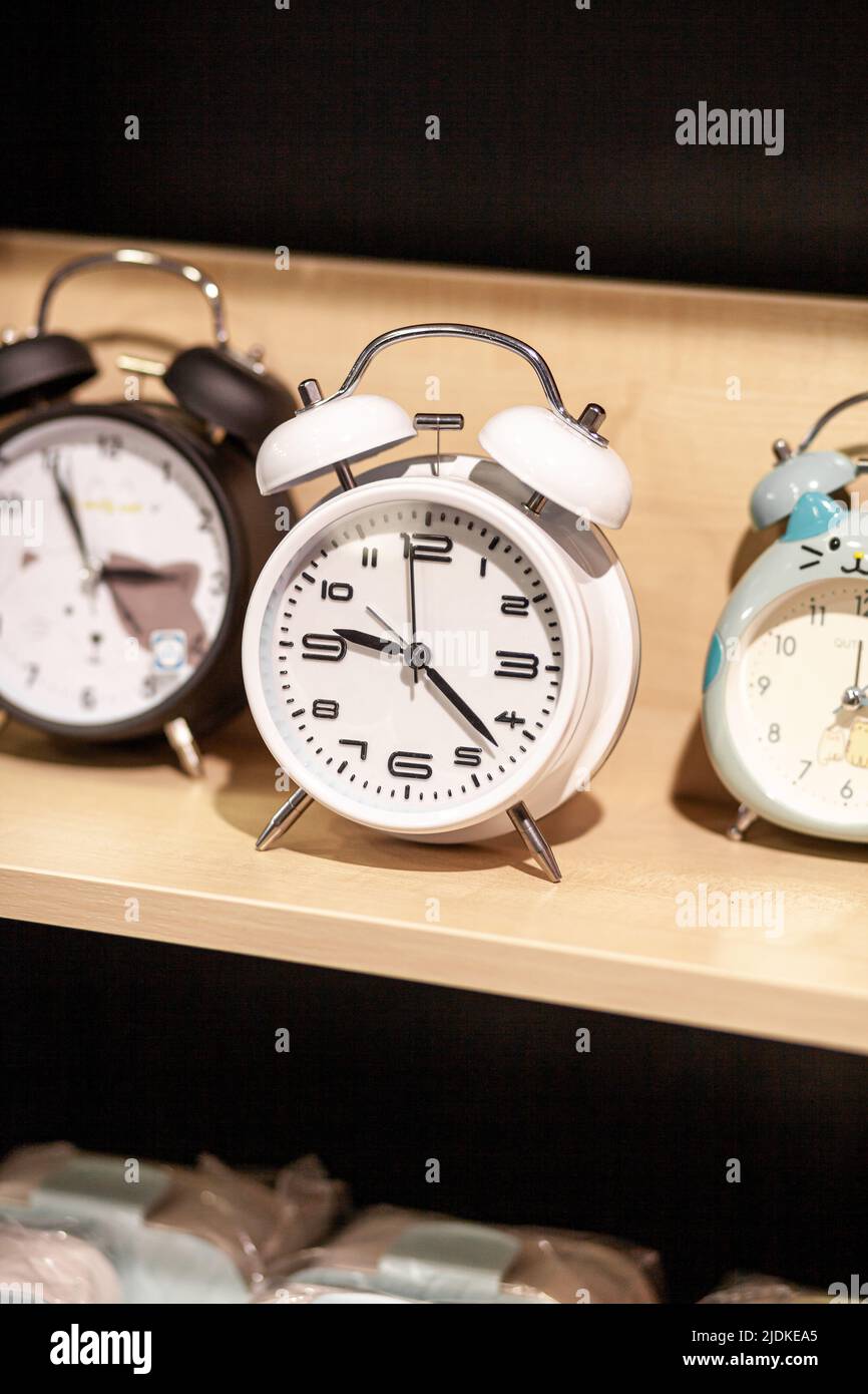 Round alarm clock on the store shelf close-up. Sale of various watches ...