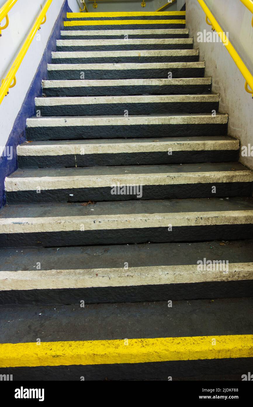 cement stair way painted with yellow and white steps and yellow hand ...
