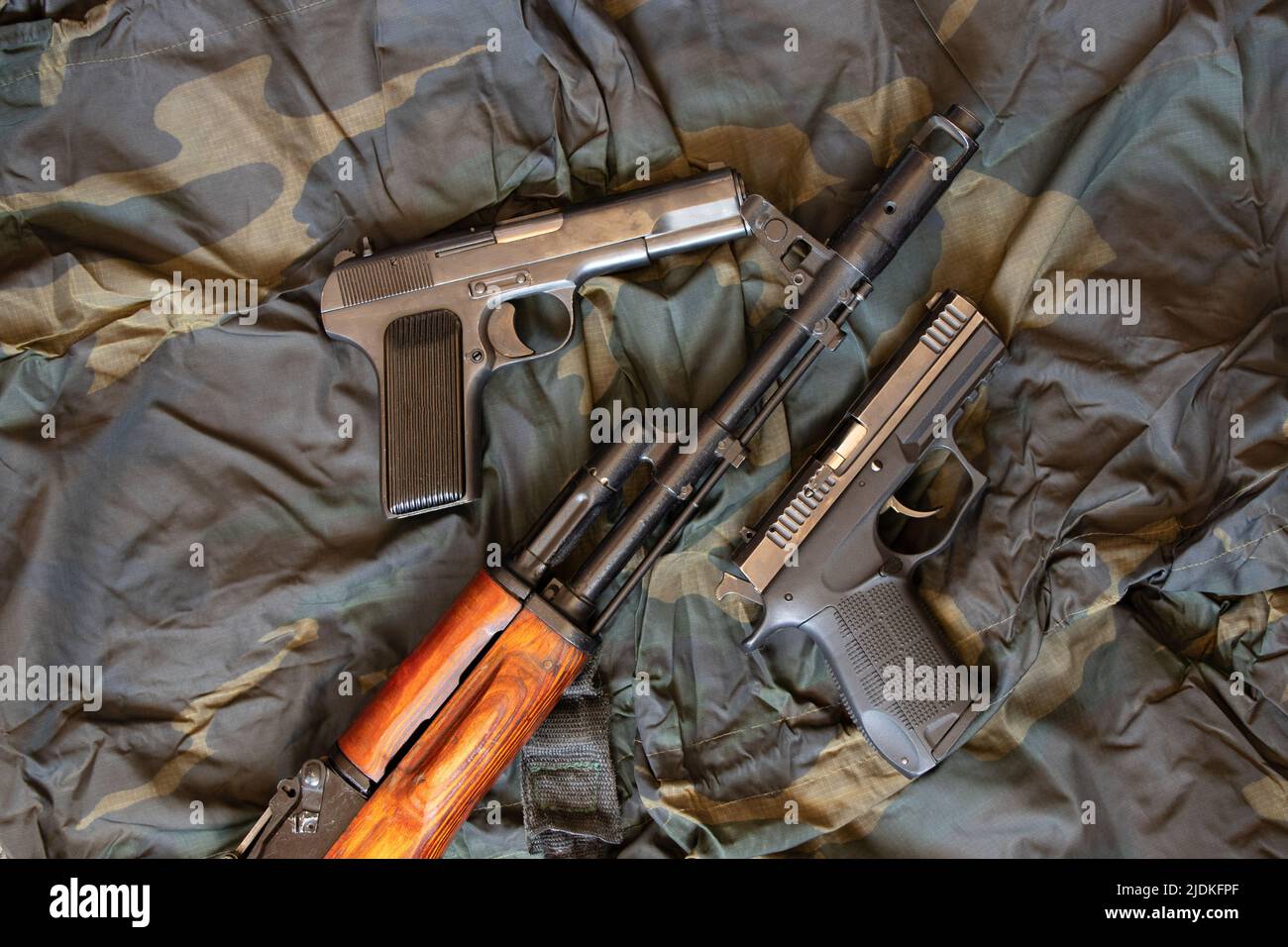 Pistols and machine gun lie on a green camouflage background, military ...