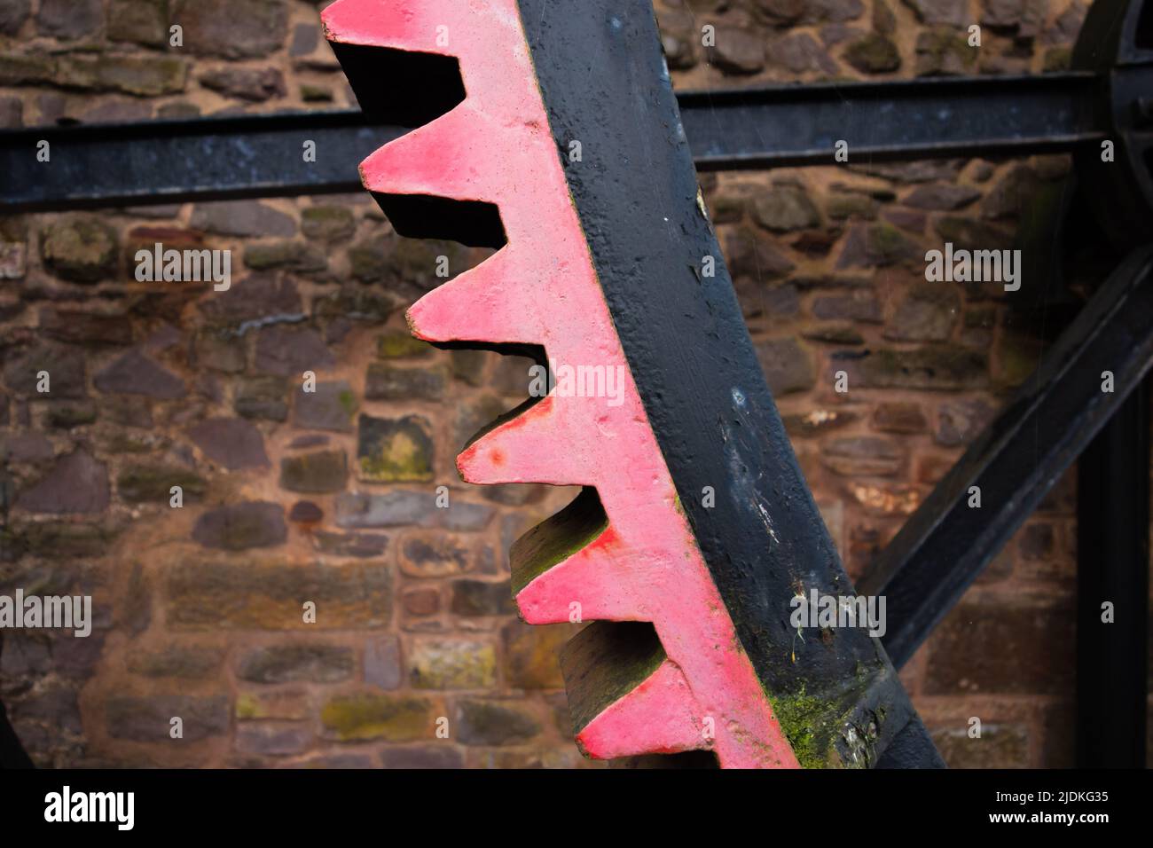 red painted giant cog wheel with old stone wall in the background Stock ...
