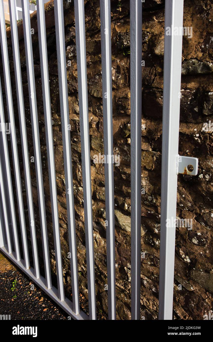 silver steel security fence against an old stone wall Stock Photo - Alamy