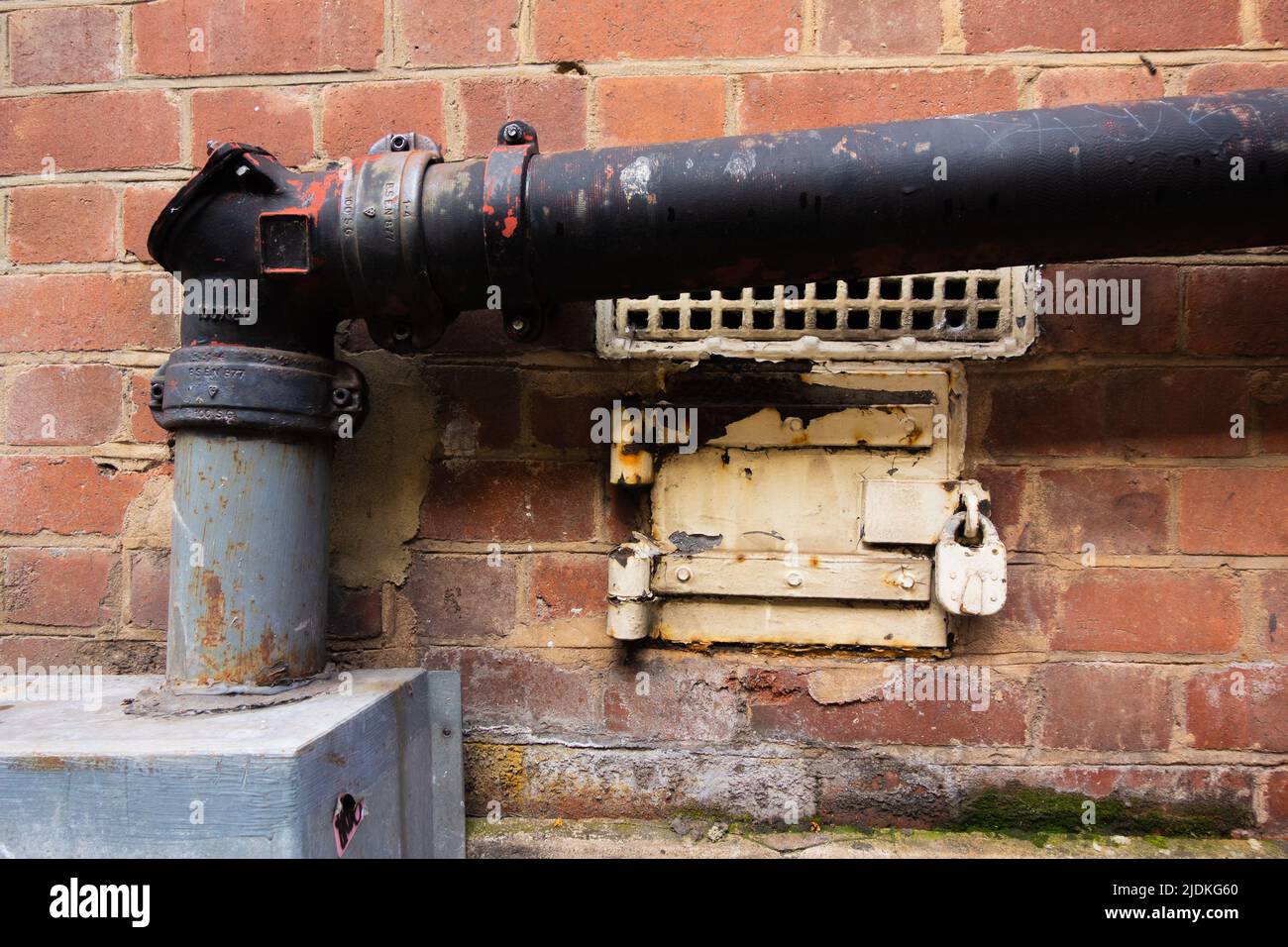 waste pipe on the side of a building with a pad locked steel door Stock ...