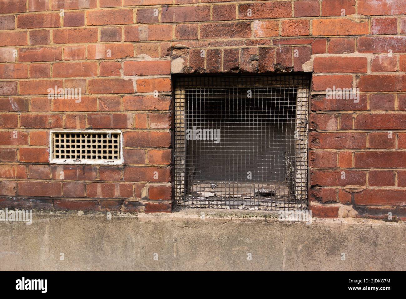 white air brick and metal grill set into a red brick wall with the ...