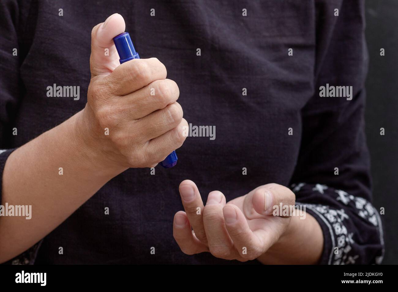 Cropped woman hands holding lancet pen to prick finger to check sugar ...