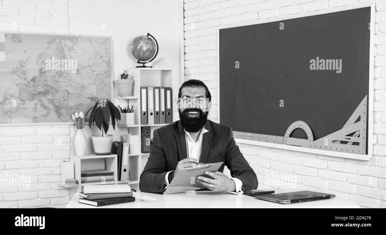 happy mature teacher making notes in paper. brutal bearded man work in ...